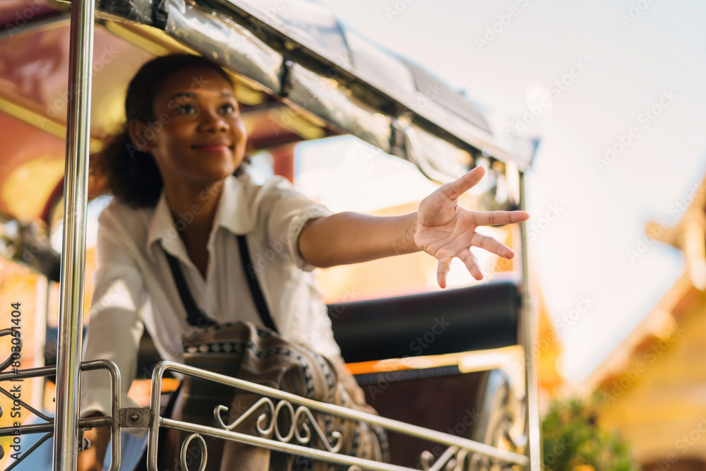 black girl travel reaching hand out riding tuk tuk car. cheerful solo ...