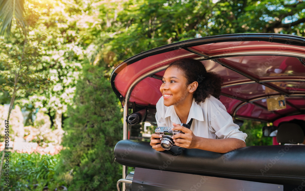 happy black traveler girl using camera outside tuk tuk ride. solo ...