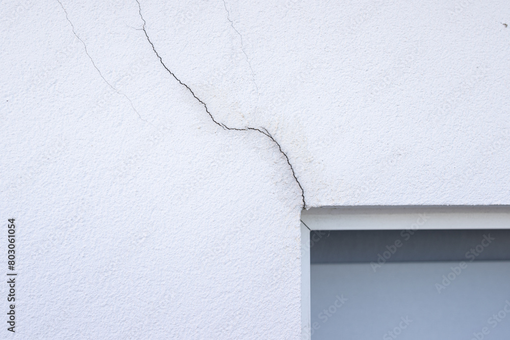 Detail of a crack in the facade cladding near the window lintel area ...