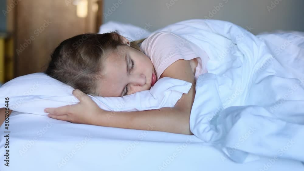 Portrait of a cute little girl lying on a cozy white pillow and under a ...