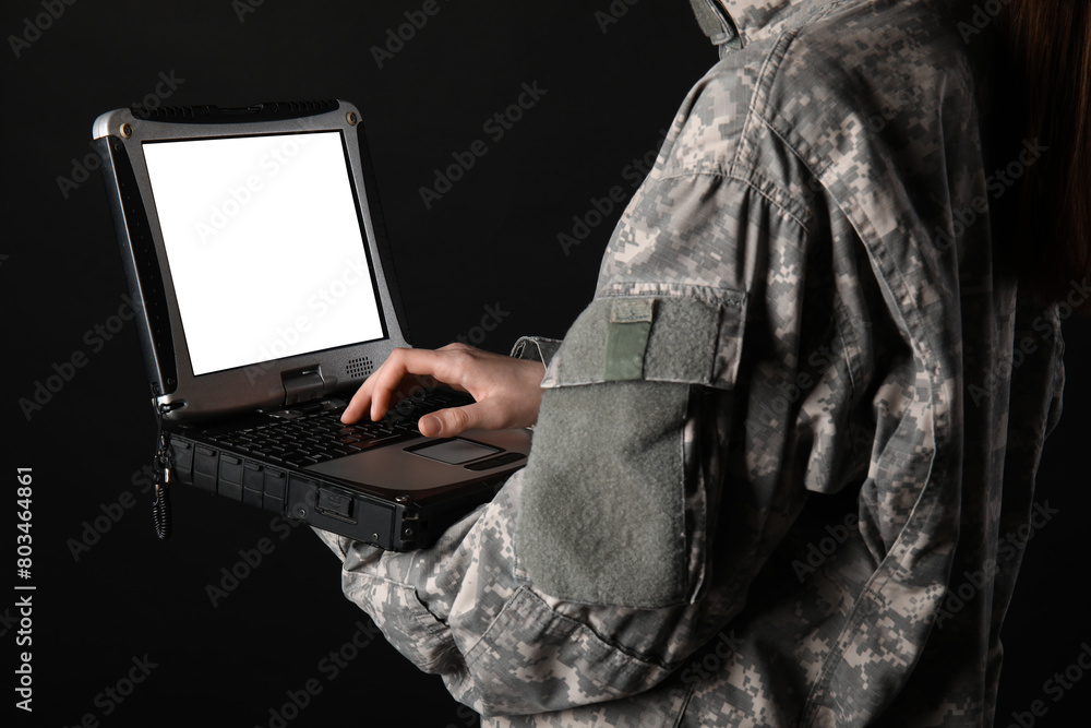 Soldier in uniform holding military laptop with blank screen on black ...