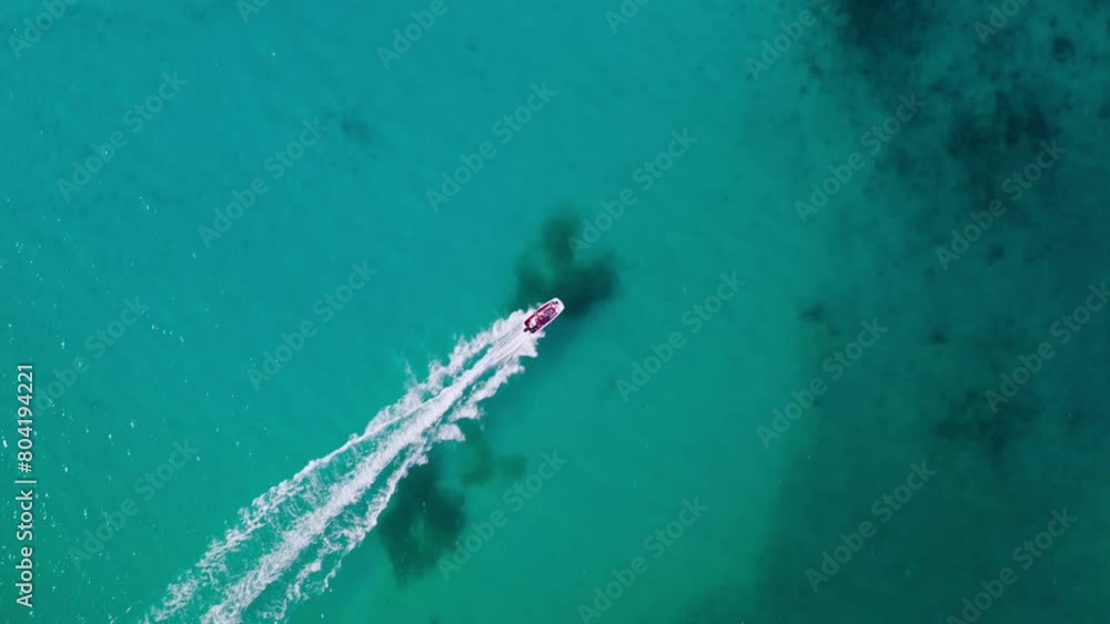 A top-down aerial view of a motorboat riding across the sea. Crystal ...