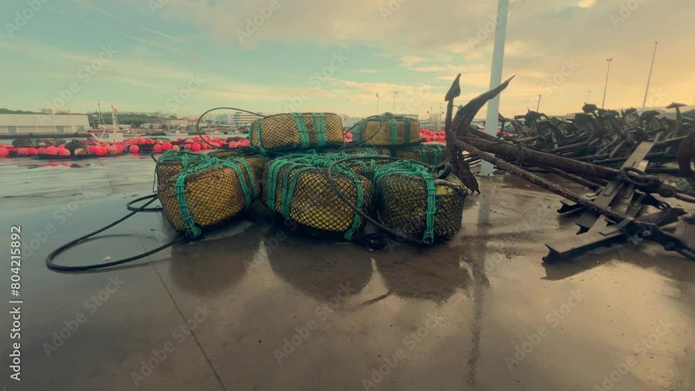 Fishing gear rests on the moist asphalt in a coastal Spanish town ...