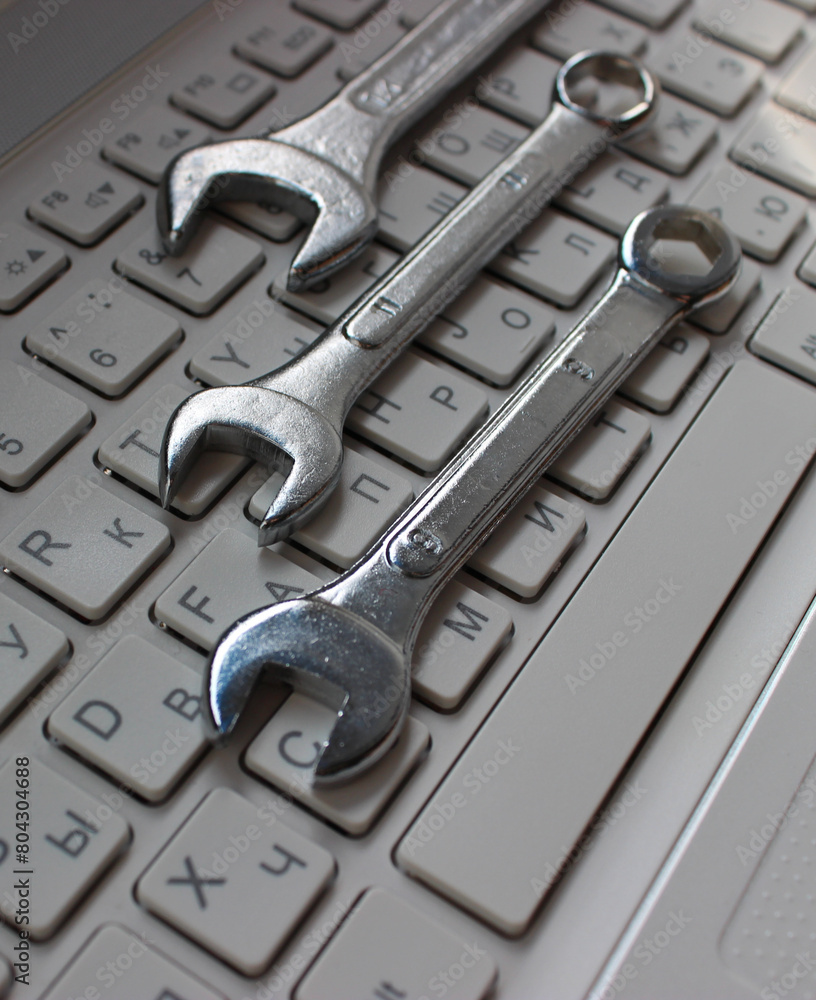 Metallic wrenches on a buttons of laptop keyboard vertical stock photo ...