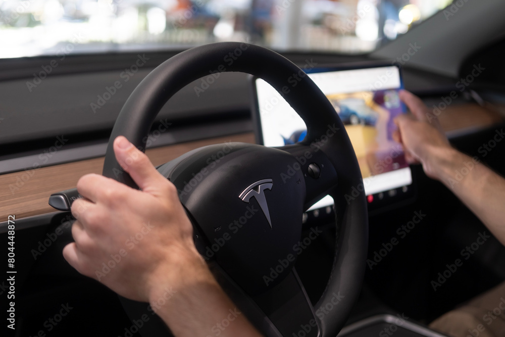 Behind steering wheel Tesla model Y electric car, male hands on Driver ...