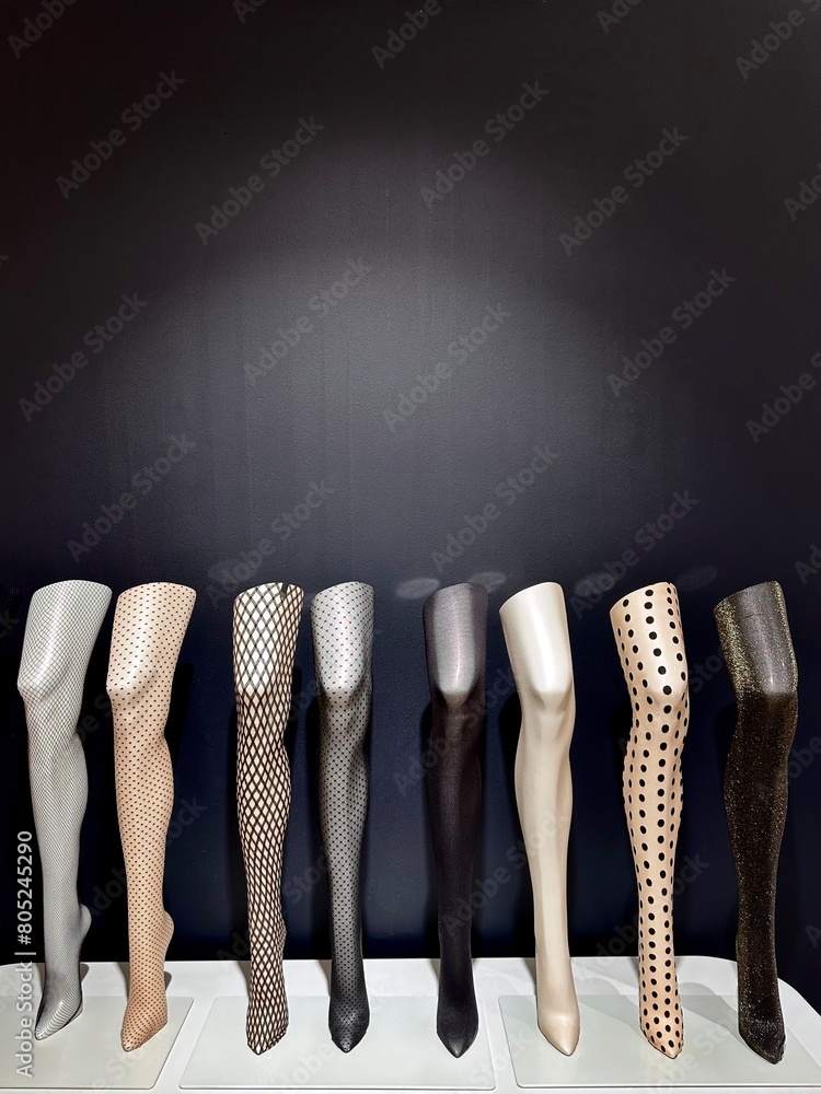 Display of a row of mannequin legs wearing assorted stockings against a ...