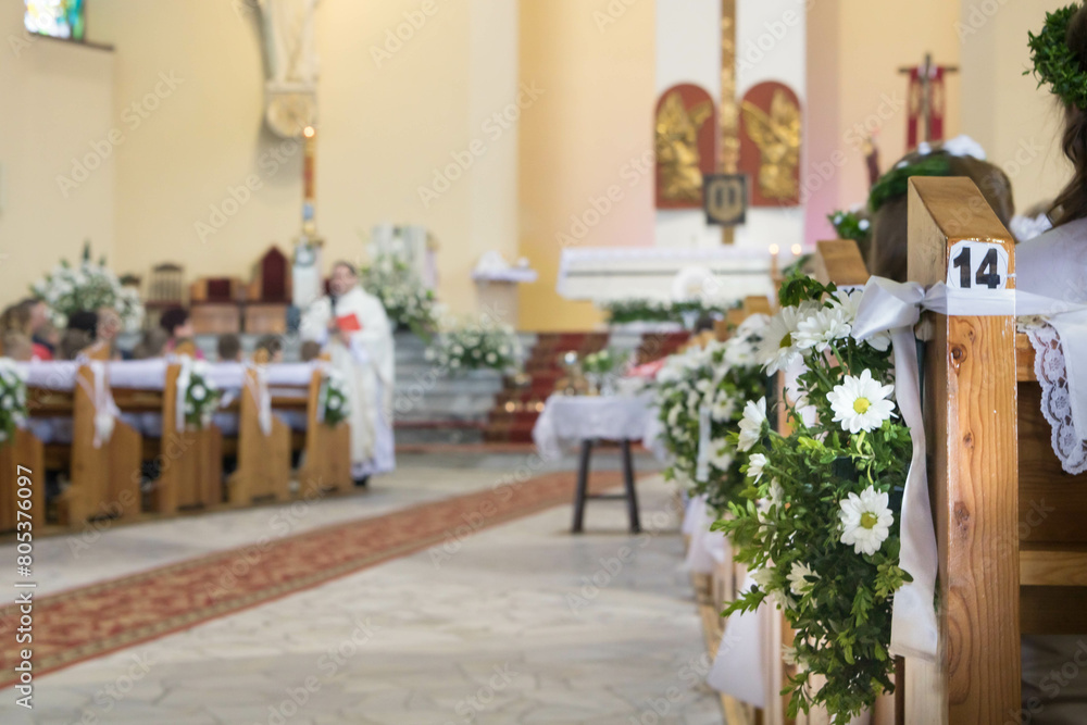 Interior of Catholic church decorated with white flowers and ribbion ...