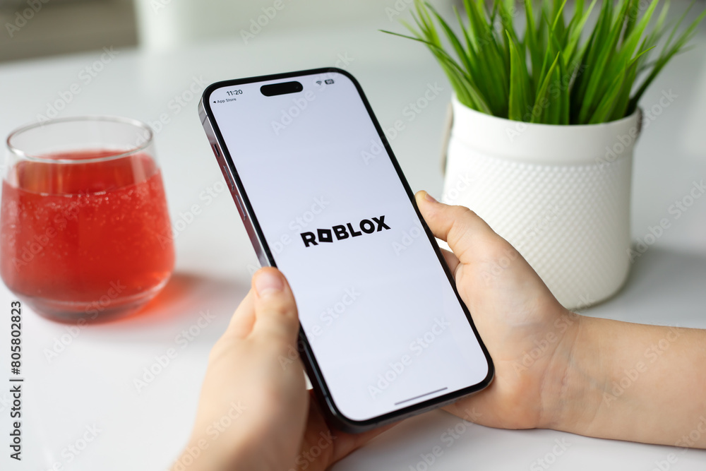 Children hands holding iPhone 15 Pro Max with game Roblox Stock Photo ...
