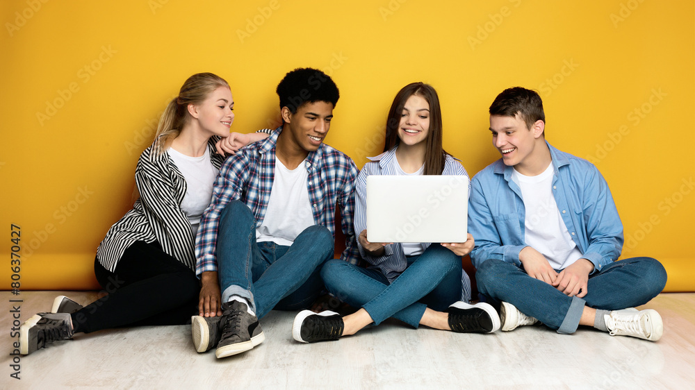 Four multiethnic teenagers are casually seated on the floor with their ...