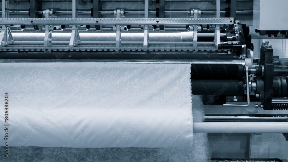 A machine is weaving a fabric with many different colored threads. The ...