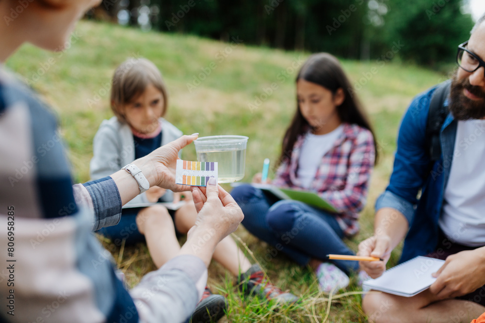Young students analyzing water quality, ph level with indicator strips ...