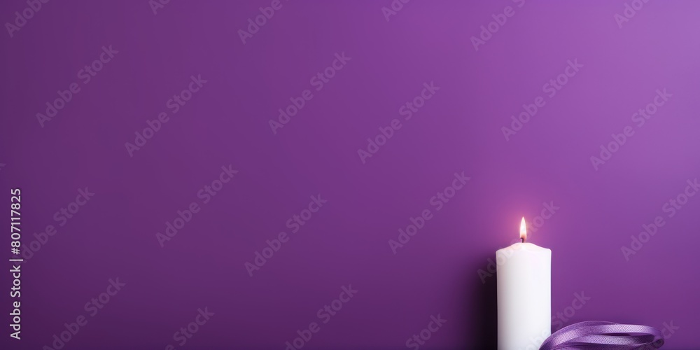 Purple background with white thin wax candle with a small lit flame for ...