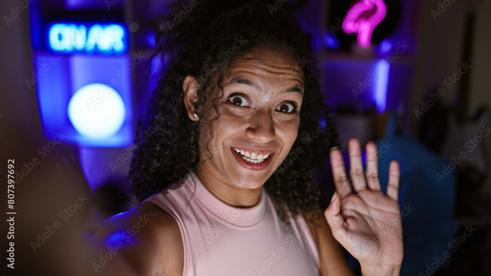 Confident curly-haired young hispanic woman streamer rocks her gaming ...