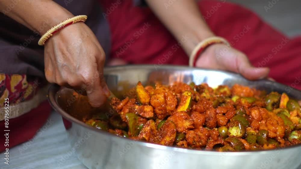 Hands of Indian woman wearing bangles mixing raw mangoes with spices to ...
