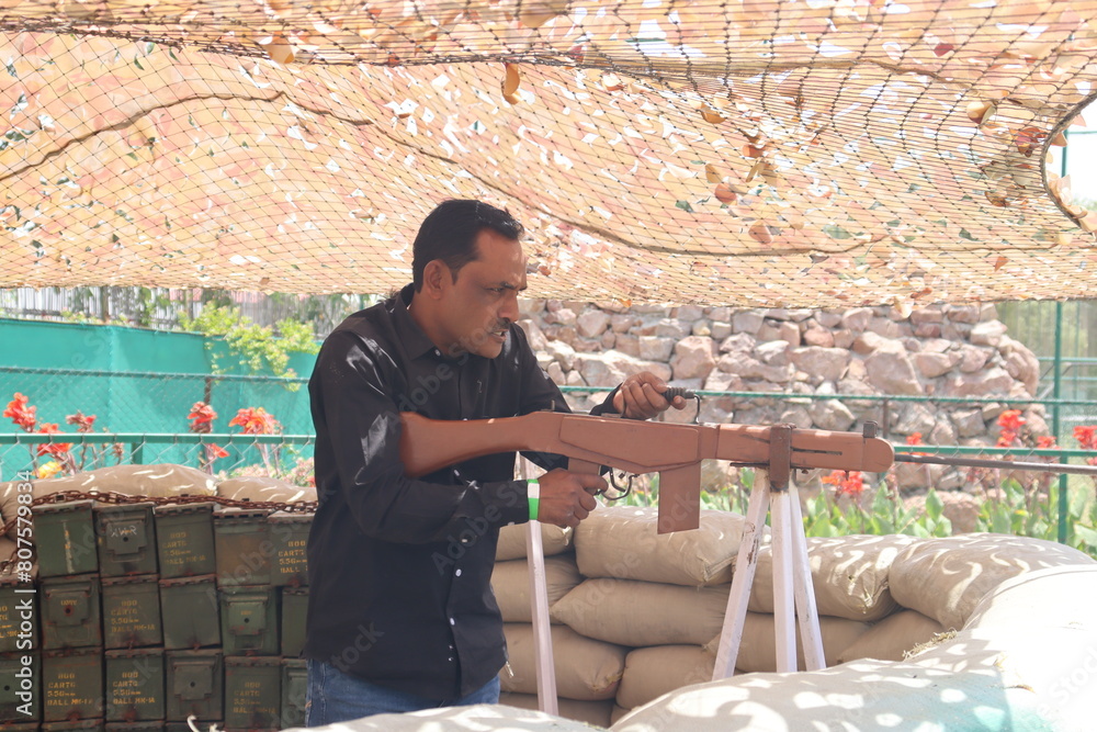 Indian man pointing out fake gun in a base camp and shooting the gun ...