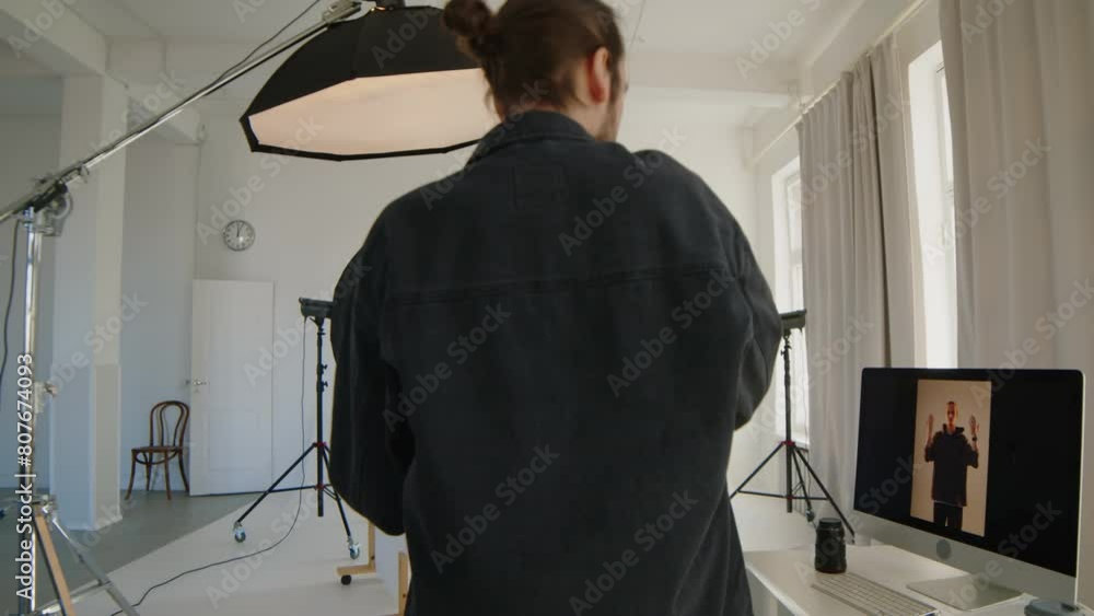 Back view arc shot of professional male photographer taking studio ...