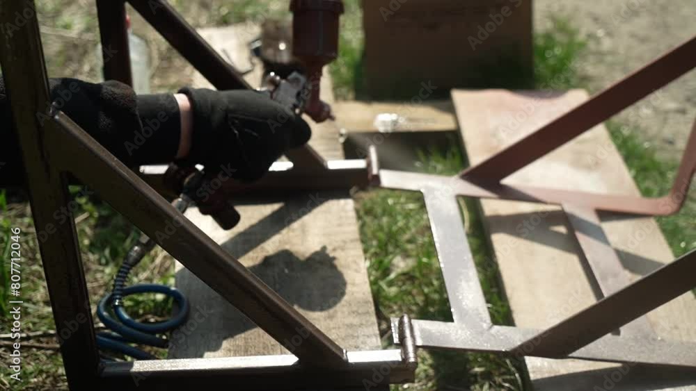 Craftsman paints a metal structure using a spray gun. Worker applies ...