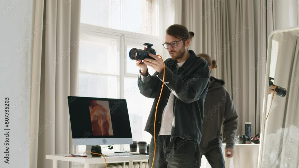 Medium shot of young photographer with assistant using dslr camera ...