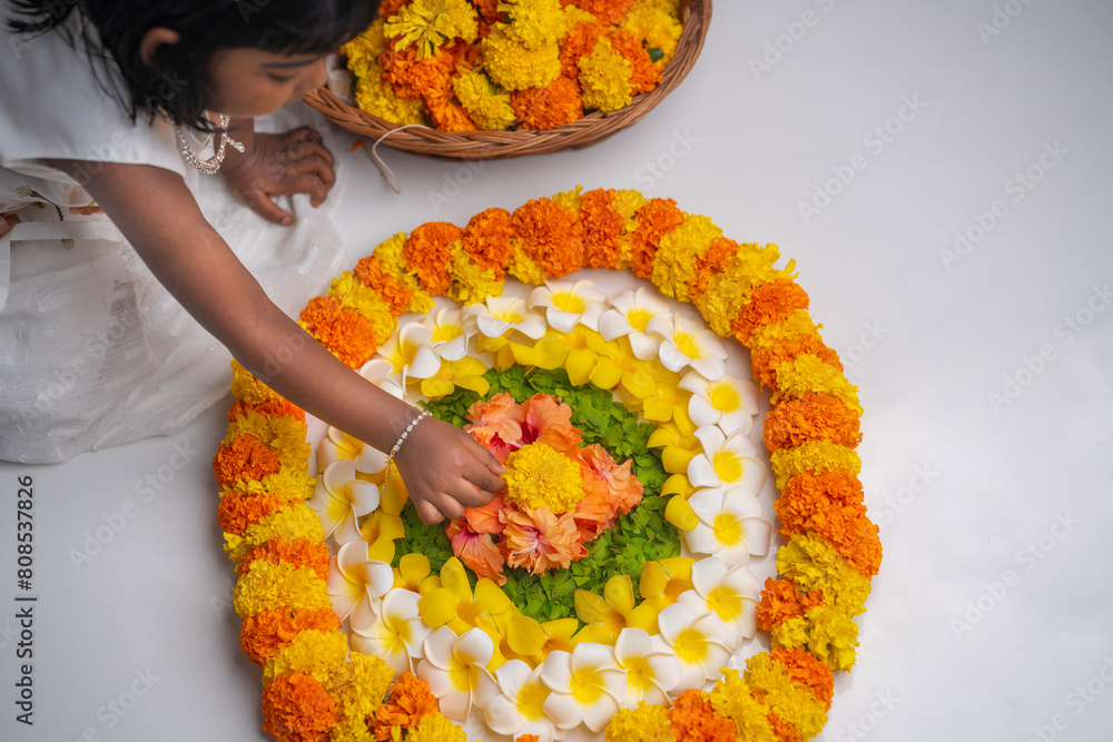 Little girl making Onam Pookalam with fresh flowers, Happy Onam ...