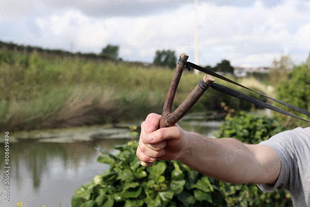 Slingshot aimed and pulled back against wrist, with hands . slingshot ...