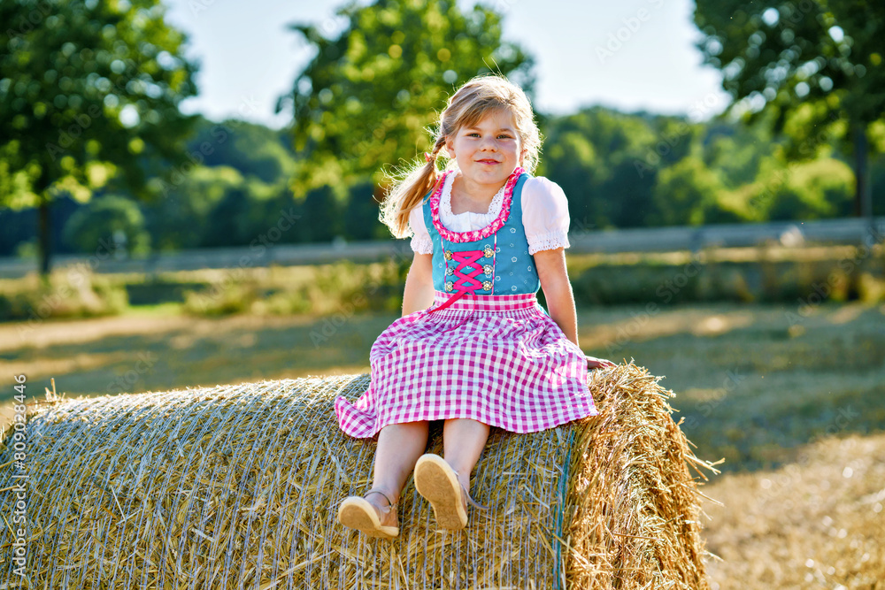 Cute little kid girl in traditional Bavarian costume in wheat field ...