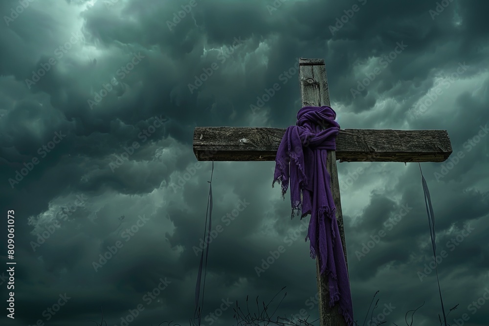 Simple wooden cross draped in purple cloth against stormy sky, setting ...