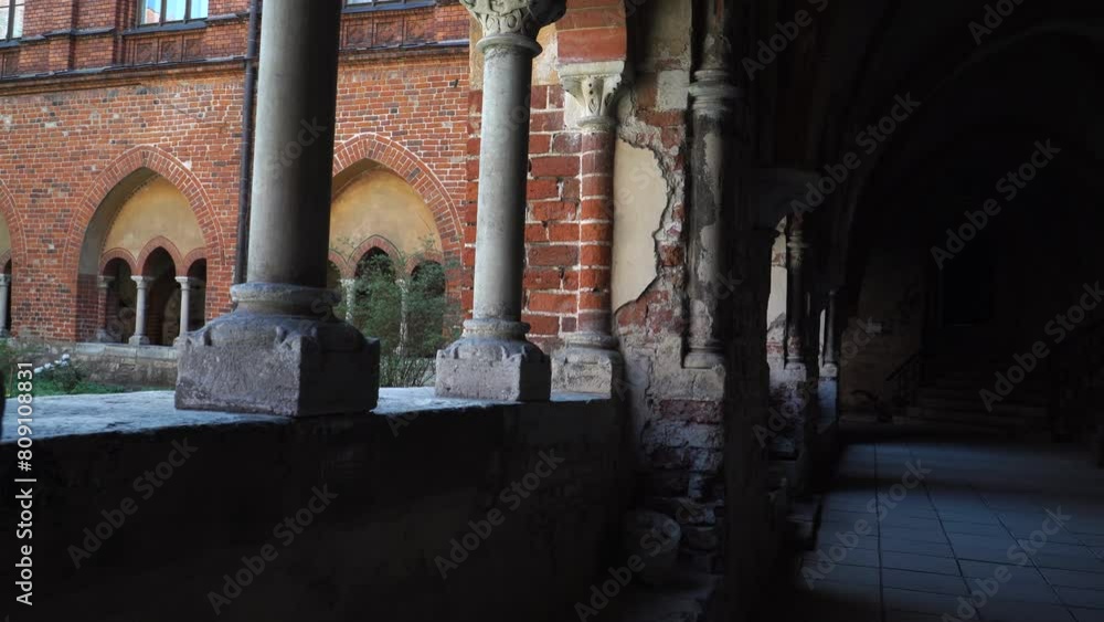 The shady corridor and red brick facade of Riga Cathedral are visible ...