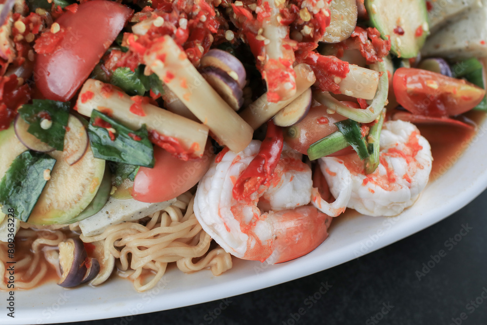 Instant noodles spicy salad with shrimp and vegetable on black table ...