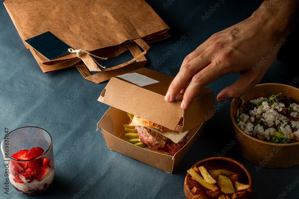 Unpacking Takeaway Food: Hand Reaching For a Burger in EcoFriendly Box ...