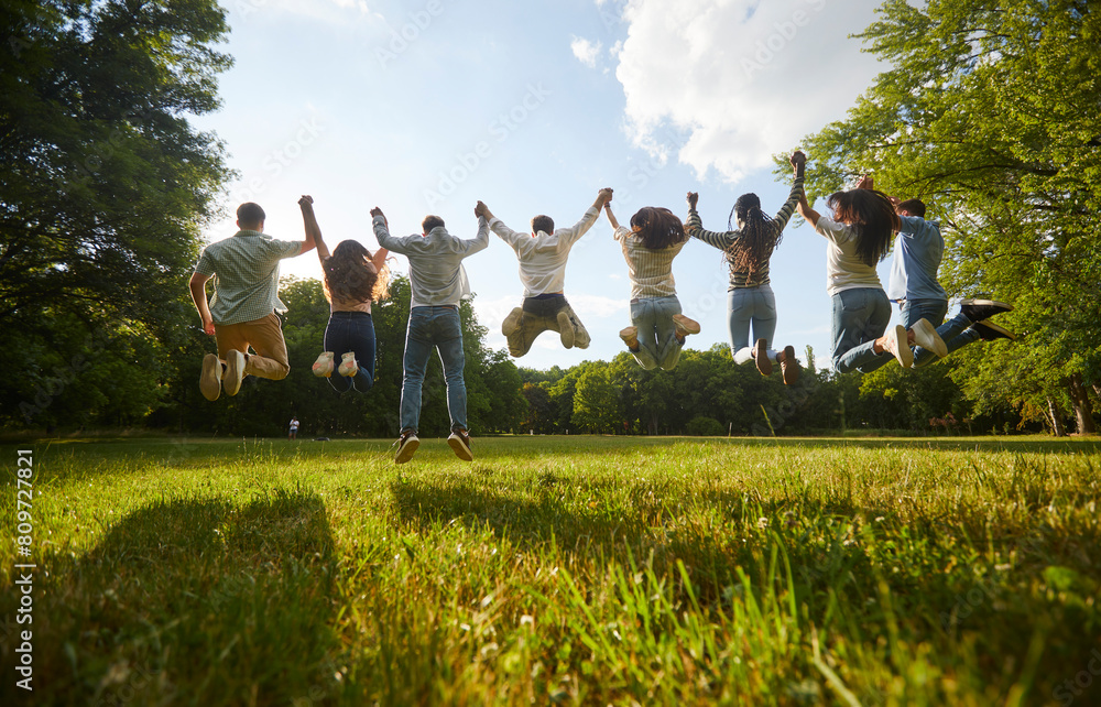 Group of friends jumping in air with raised hands while having fun in ...