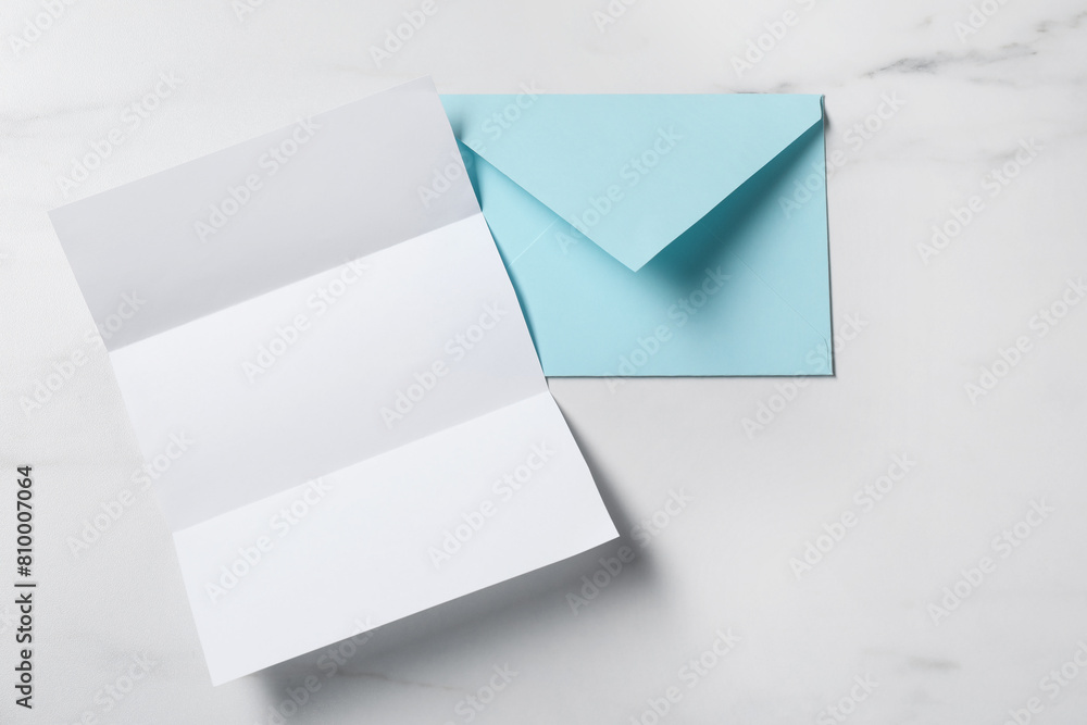 Blank sheet of paper and letter envelope on white marble table, top ...