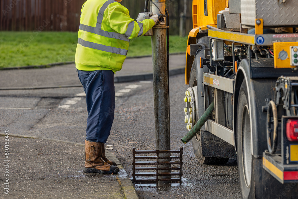 Gully sewer drain jet cleaning. MVC tanker truck operative uses suction ...