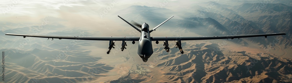 A military drone armed with missiles patrols over rugged mountainous ...