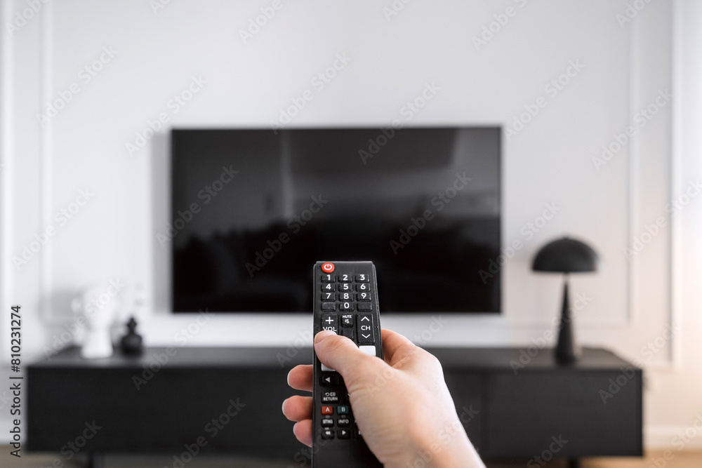 Woman hand hold remote control, press button and turn on television ...