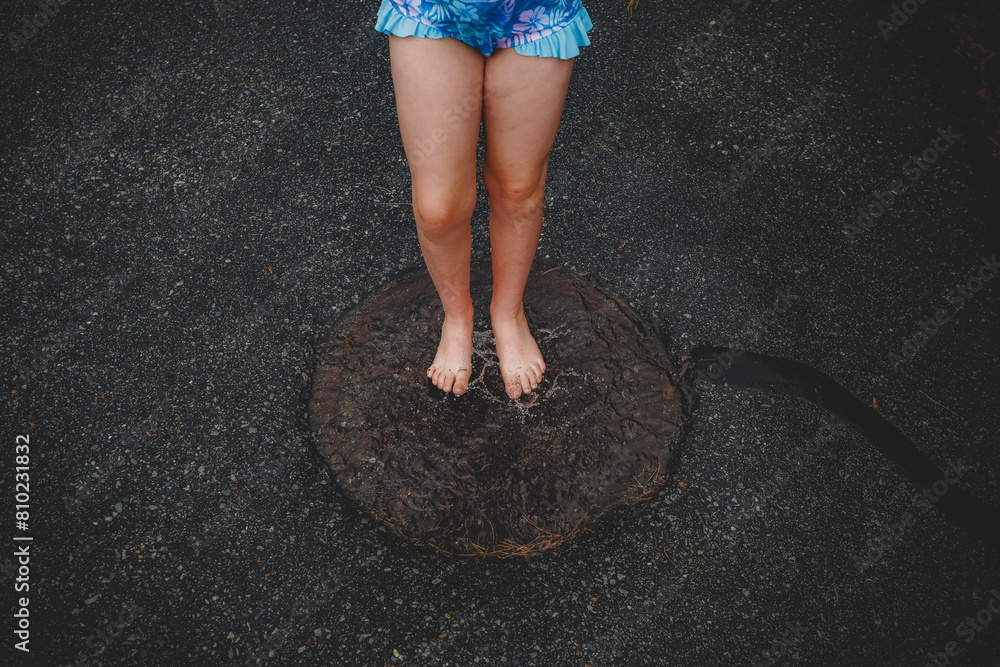 feet splashing in a puddle over a manhole cover Stock Photo | Adobe Stock