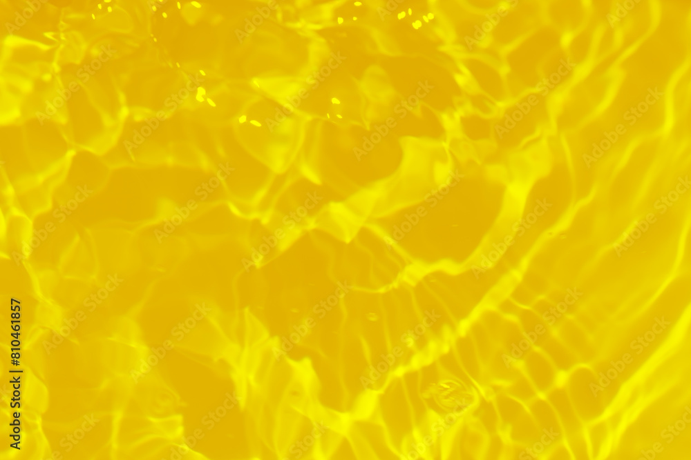 Yellow water with ripples on the surface. Defocus blurred transparent ...