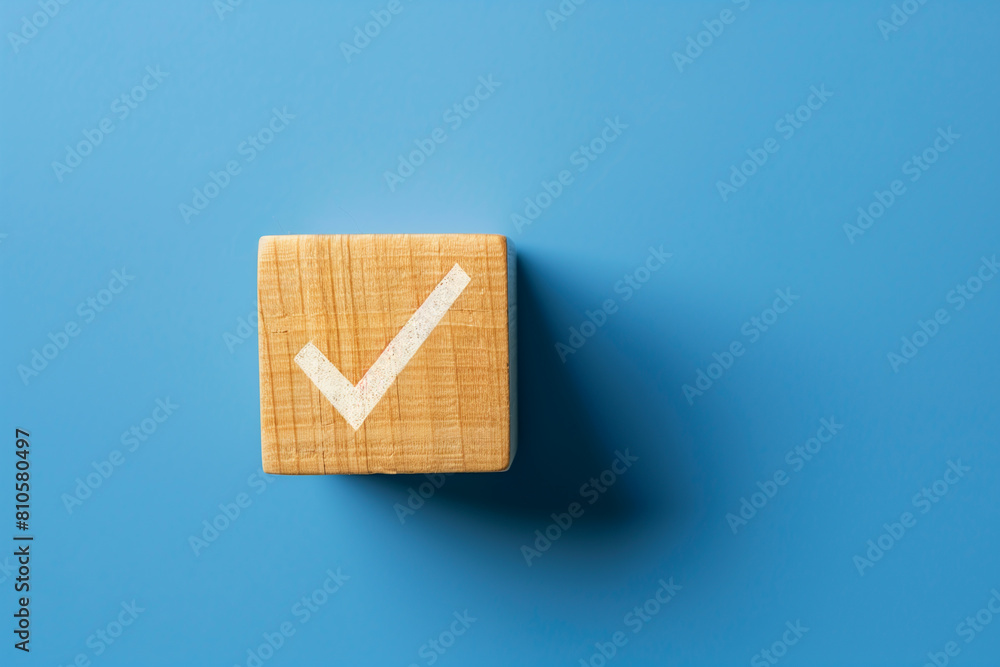 Wooden block with white check mark against blue background representing ...