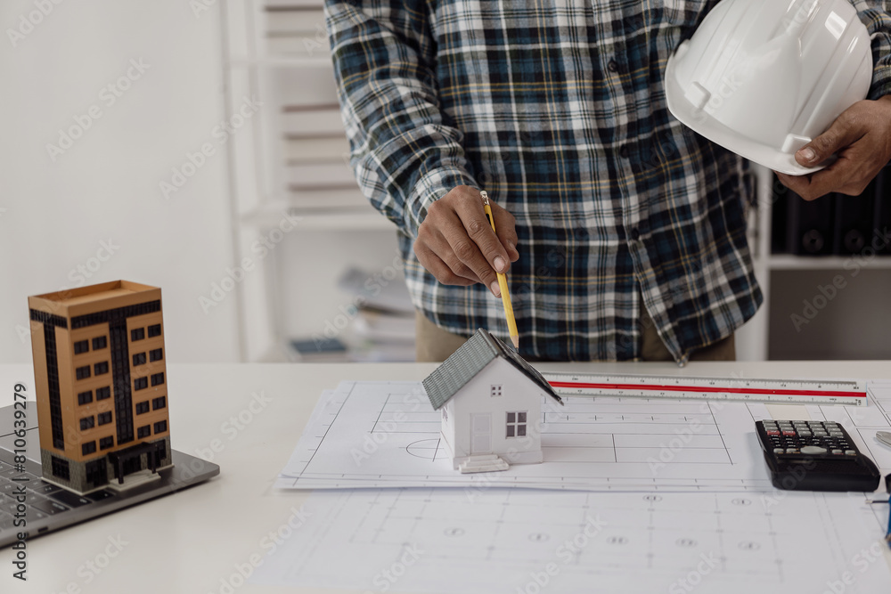 Engineer points to building on blueprint and uses laptop to draw ...
