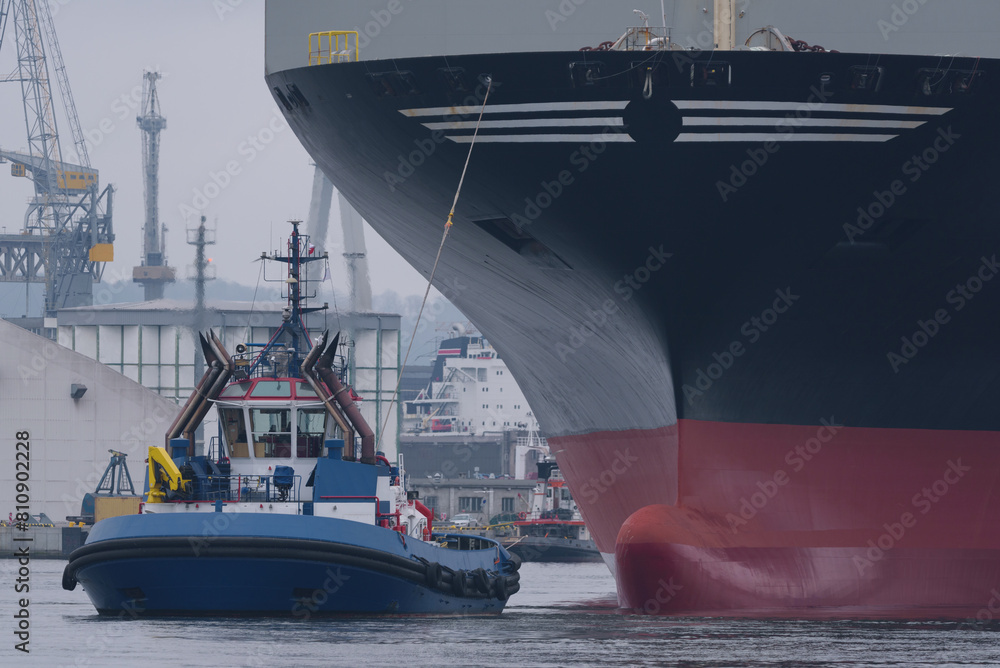MARITIME TRANSPORT - A tugboat maneuvers with a ship in a seaport Stock ...