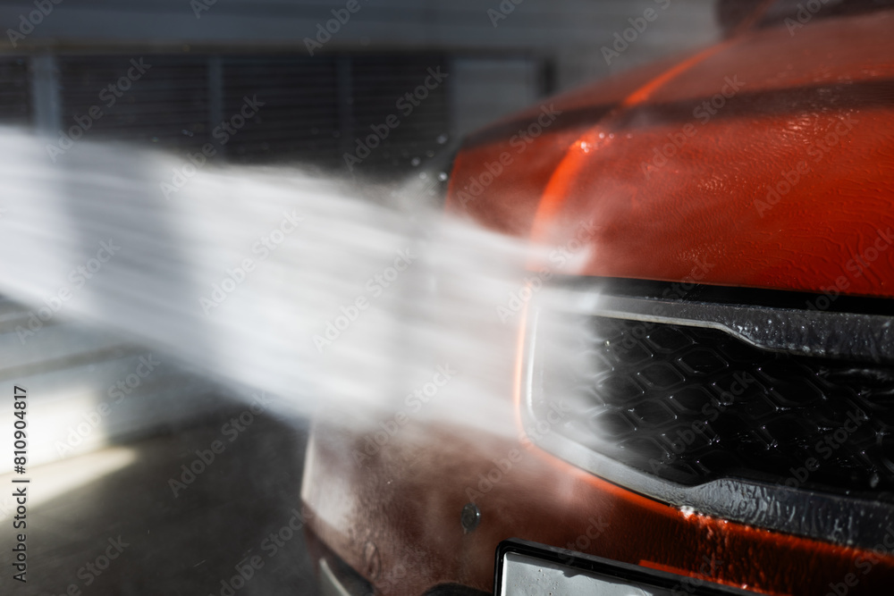 Close-up of a jet of water being sprayed onto a car from a gun in a car ...