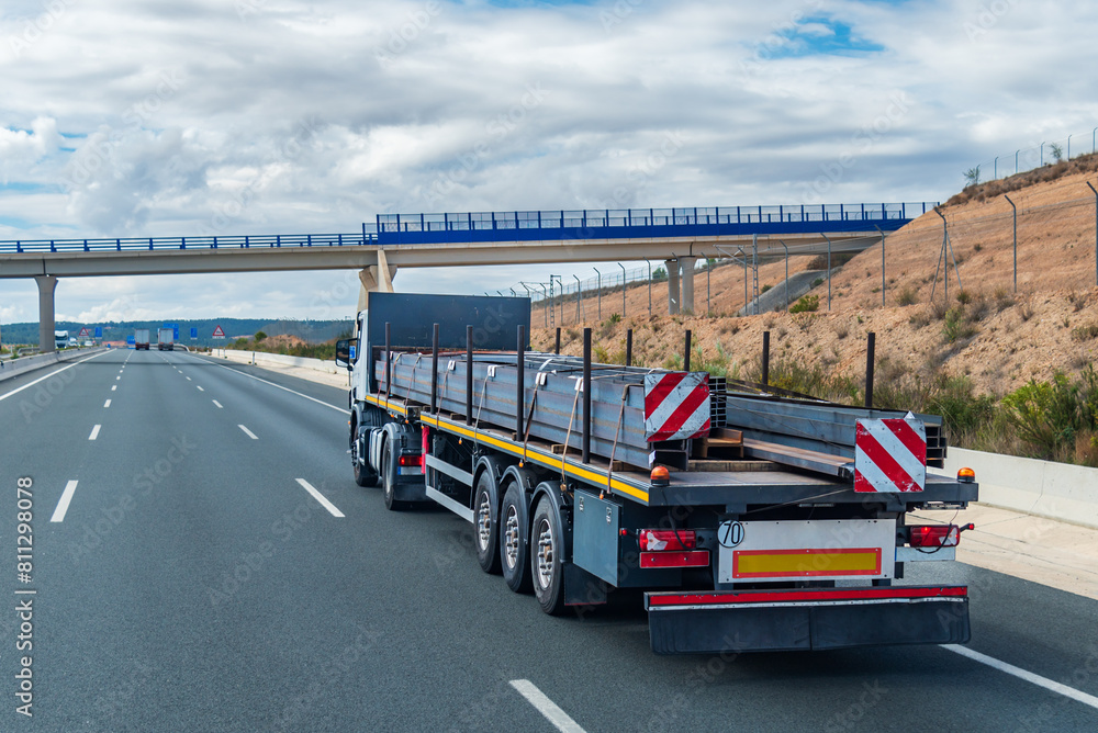 Truck loaded with iron beams, oversized load with its signaling panels ...