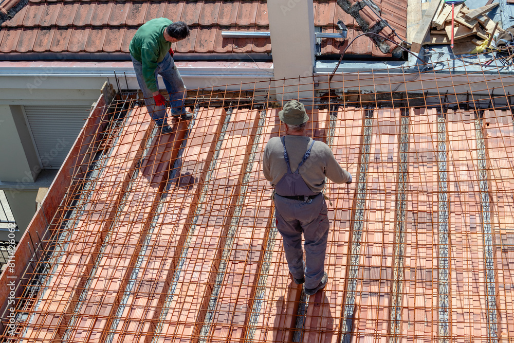 Construction workers prepare a steel mesh to reinforce a roof slab ...