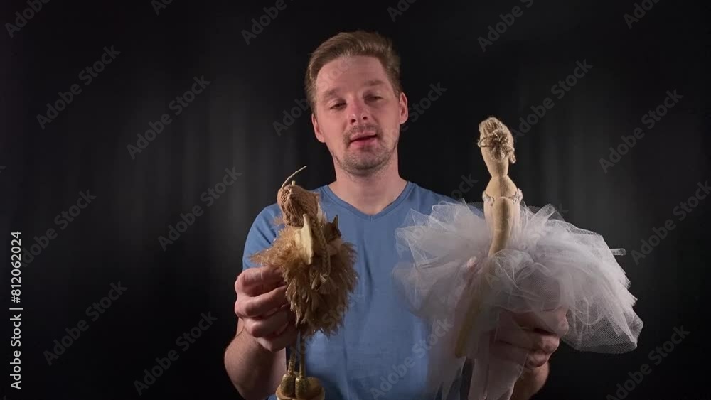 A portrait of a handsome young white man holding puppets, playing with ...