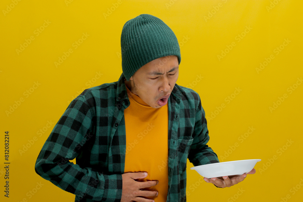Distressed young Asian man, clutching his stomach and an empty white ...