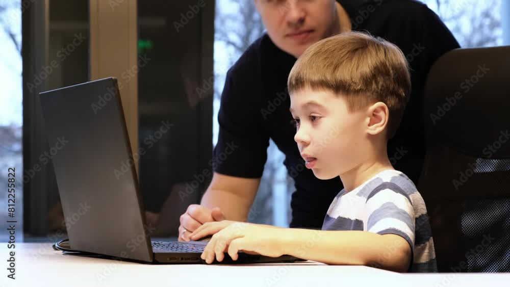 A teacher looks as a 6 year child solve a problem using laptop. Checks ...