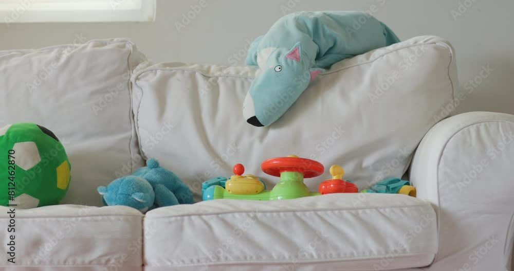 A cluttered living room scene with a white couch overflowing with ...