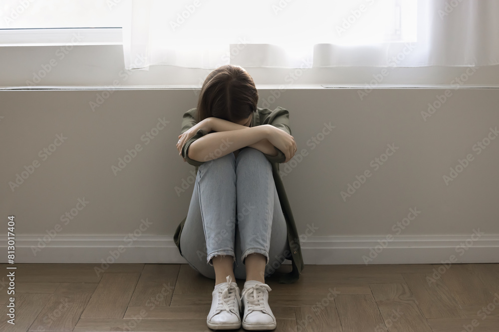 Unhappy lonely stressed young teen girl sitting on floor at wall ...