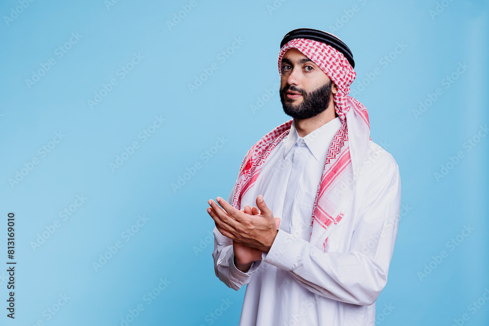 Serious arab man dressed in traditional clothes applauding and showing ...