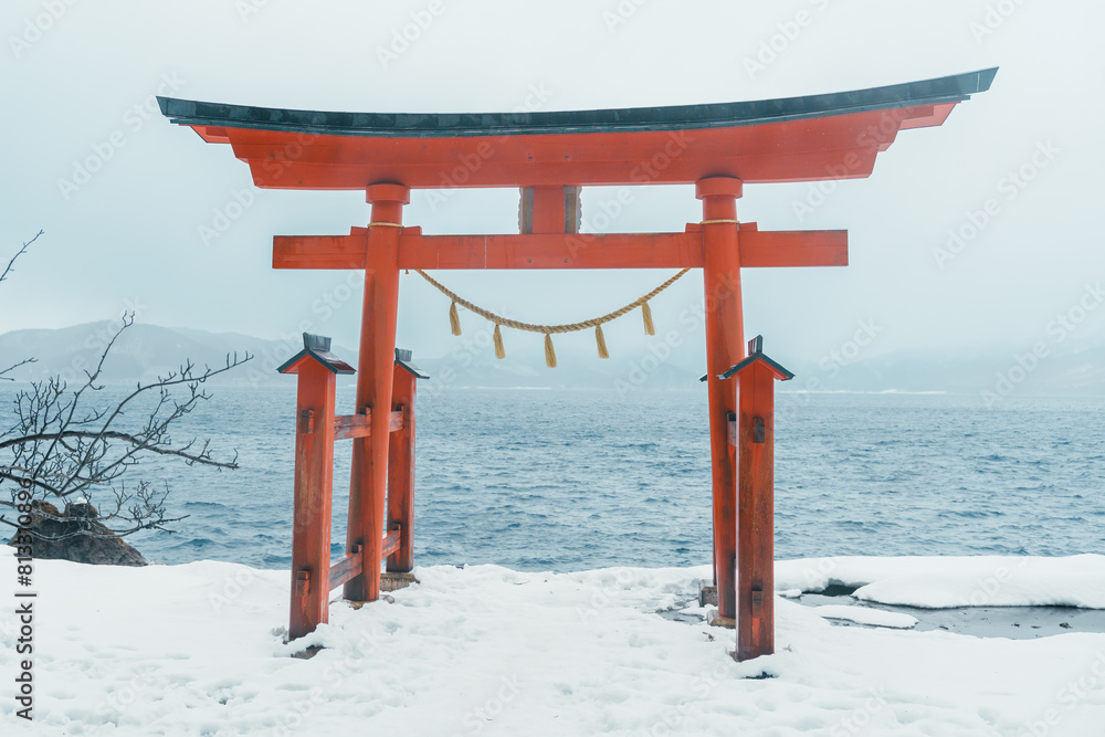 Red Japanese Torii gate of Goza no Ishi Shrine at lake tazawa in winter ...