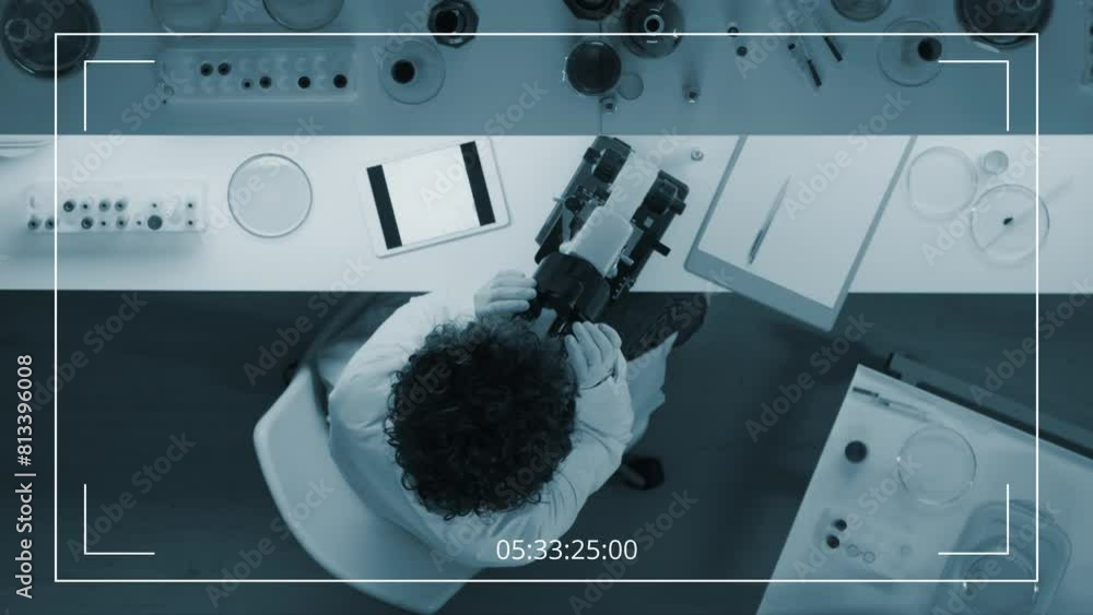 Overhead surveillance footage of female scientist examining tissue ...